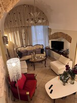 Sala de estar com sofá, poltronas, mesa de centro, televisão e um arco decorativo.