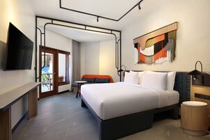 Quarto de hotel moderno com uma cama grande, uma escrivaninha, televisão de tela plana e uma varanda com vista.