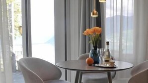 Uma área de jantar moderna com uma mesa redonda, quatro cadeiras e um vaso com flores.