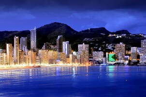 Linha do horizonte urbana com edifícios altos e um corpo d'água em primeiro plano.