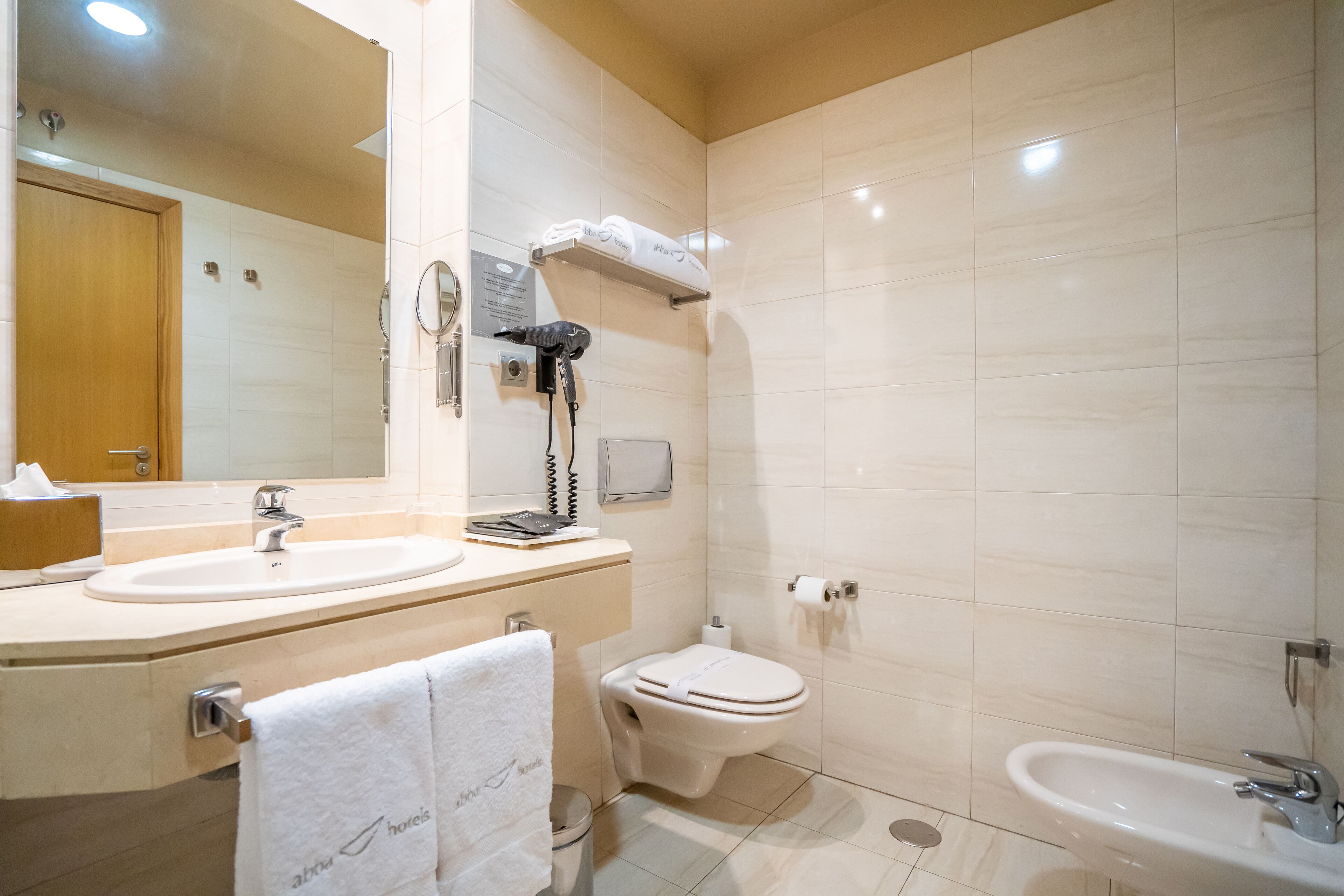 Uma casa de banho moderna com lavatório, sanita e bidé.