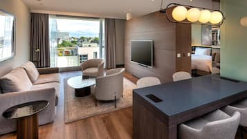 Uma sala de estar moderna com um sofá, cadeiras, uma mesa de centro e uma televisão.