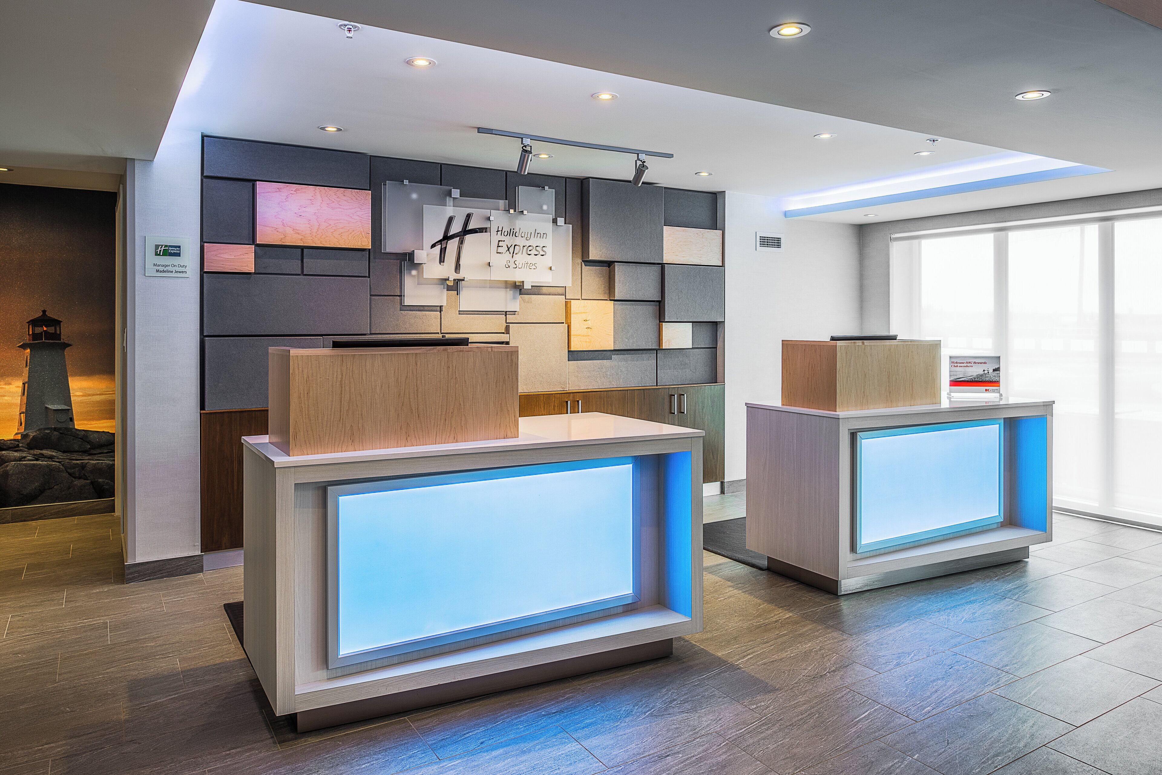 Uma receção com um painel digital, uma placa na parede e um design de interiores moderno.