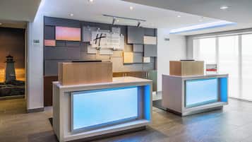 Uma receção com um painel digital, uma placa na parede e um design de interiores moderno.