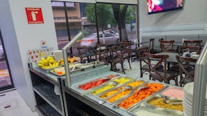 Uma área de buffet com diversas opções de comida e um aviso de extintor de incêndio na parede.