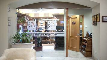 Entrada de hotel com placa da Sleep Inn, um vaso de planta, uma estante de madeira e piso de azulejos.