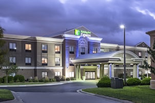 Um hotel Holiday Inn Express com fachada de tijolos, entrada coberta e gramado bem cuidado.
