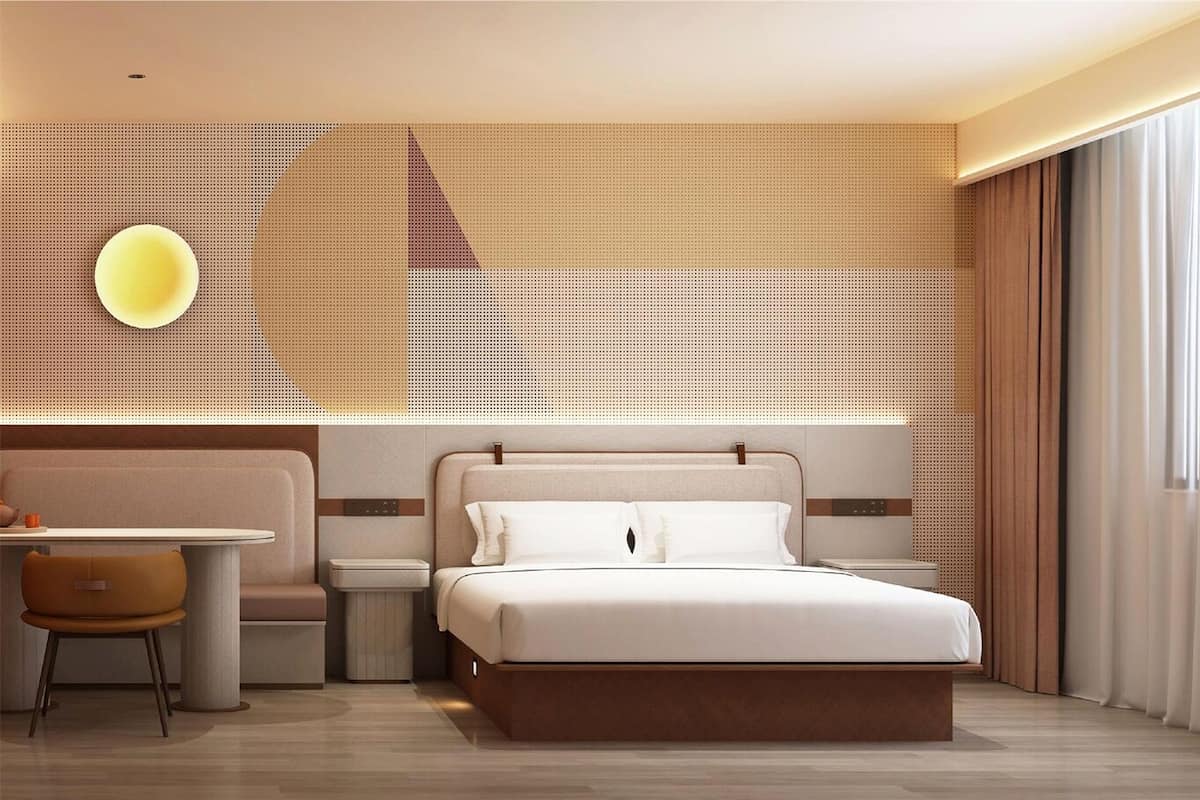 Quarto de hotel moderno com cama, mesas de cabeceira, escrivaninha e uma cadeira.