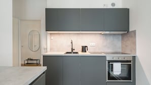 Uma cozinha moderna com armários cinza, forno embutido e coifa de aço inoxidável.