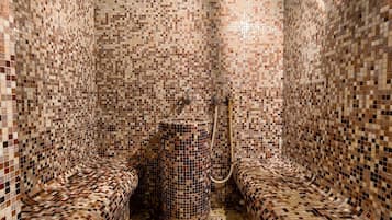 Um banheiro com azulejos em mosaico, um banco e uma pia.