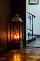Um canto iluminado por um candeeiro, uma escadaria e um chão em azulejos.