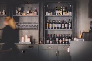 Uma área de bar com prateleiras cheias de garrafas de bebidas e copos.