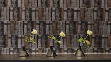 Três rosas brancas em vasos sobre um balcão, em frente a uma estante de livros.