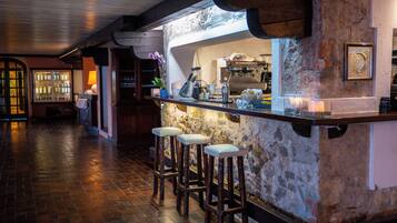 Uma área de bar com banquetas, balcão e parede de pedra.