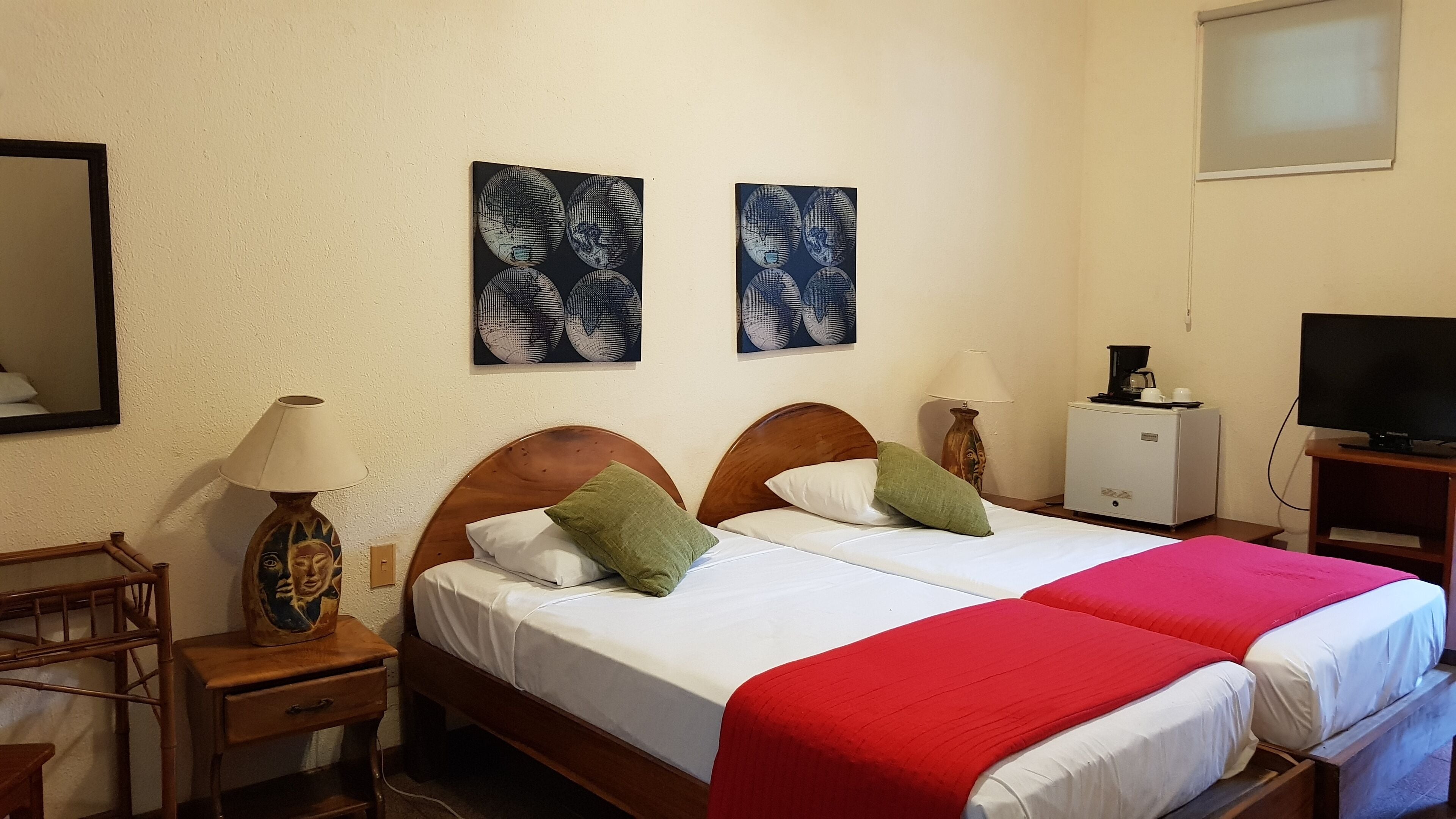 Quarto de hotel com duas camas, televisão, escrivaninha e abajur.