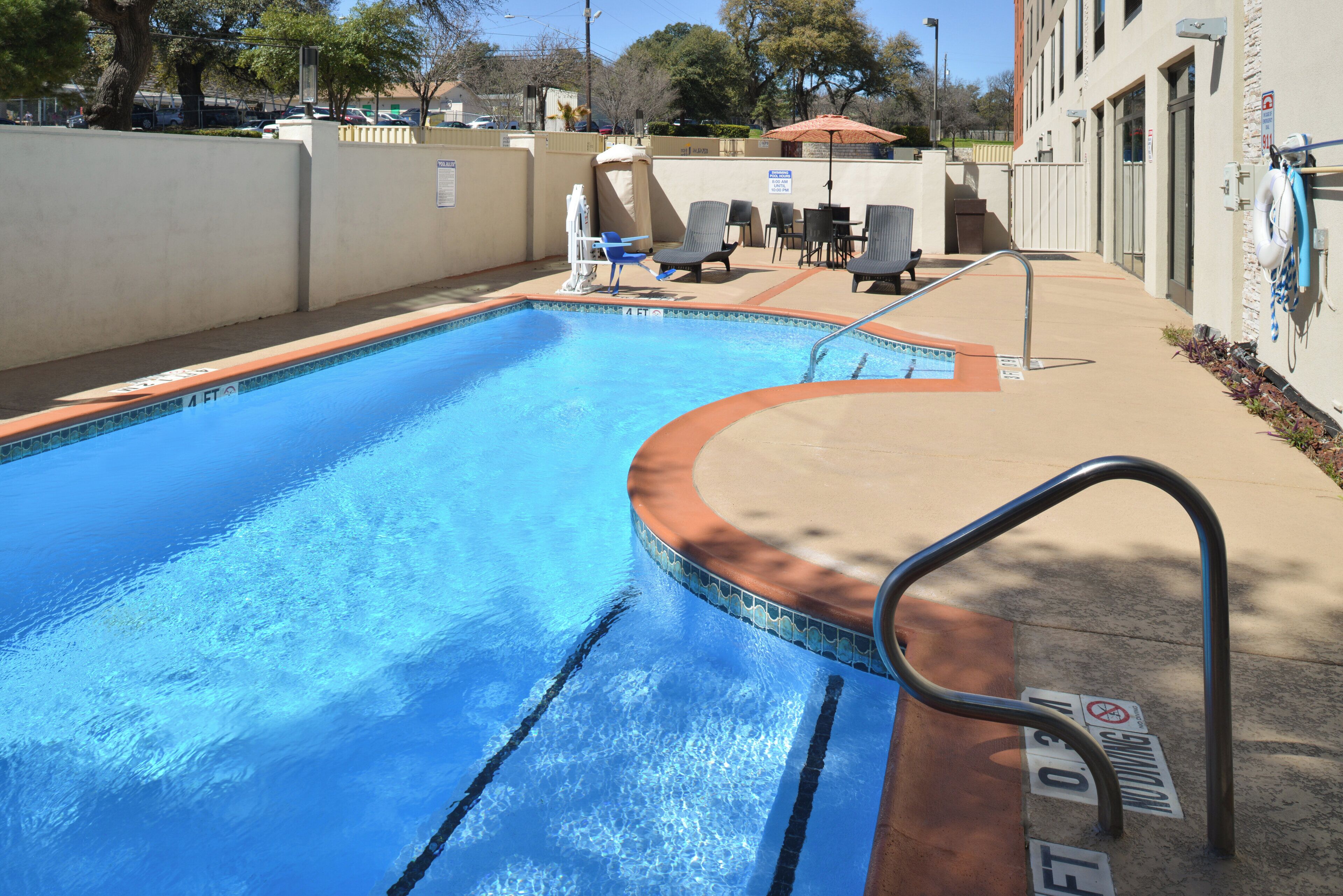 Piscina com indicador de profundidade de 1,2 metros, área de lazer com cadeiras e posto de salva-vidas.