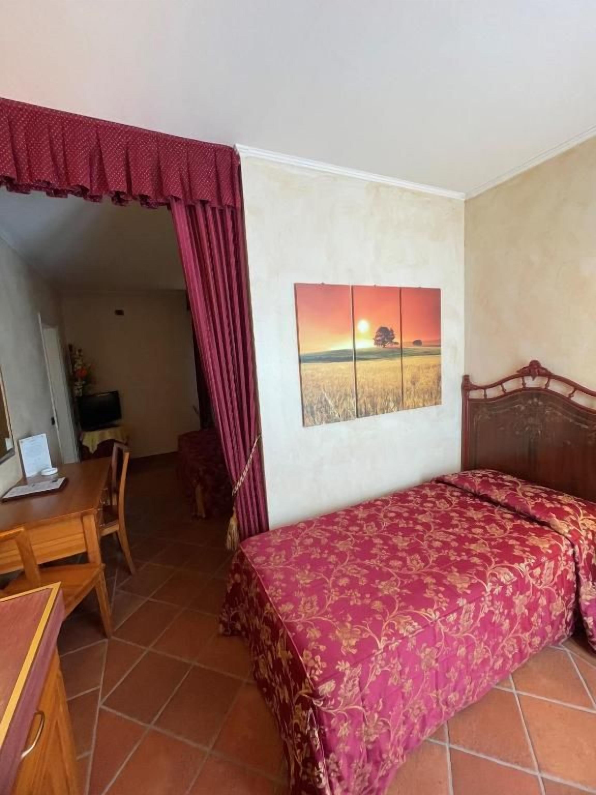 Quarto com cama, escrivaninha e cadeira. Há um quadro na parede.