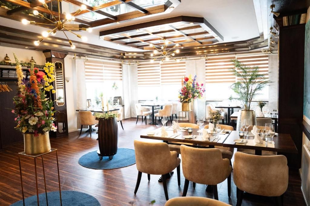 Interior de restaurante com piso de madeira, mesas redondas e cadeiras.