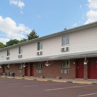 Um motel com uma fileira de quartos, cada um com janela e porta.