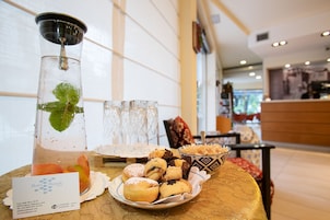 Uma mesa com um copo de chá gelado, um prato de doces e um cartão de visita de hotel.