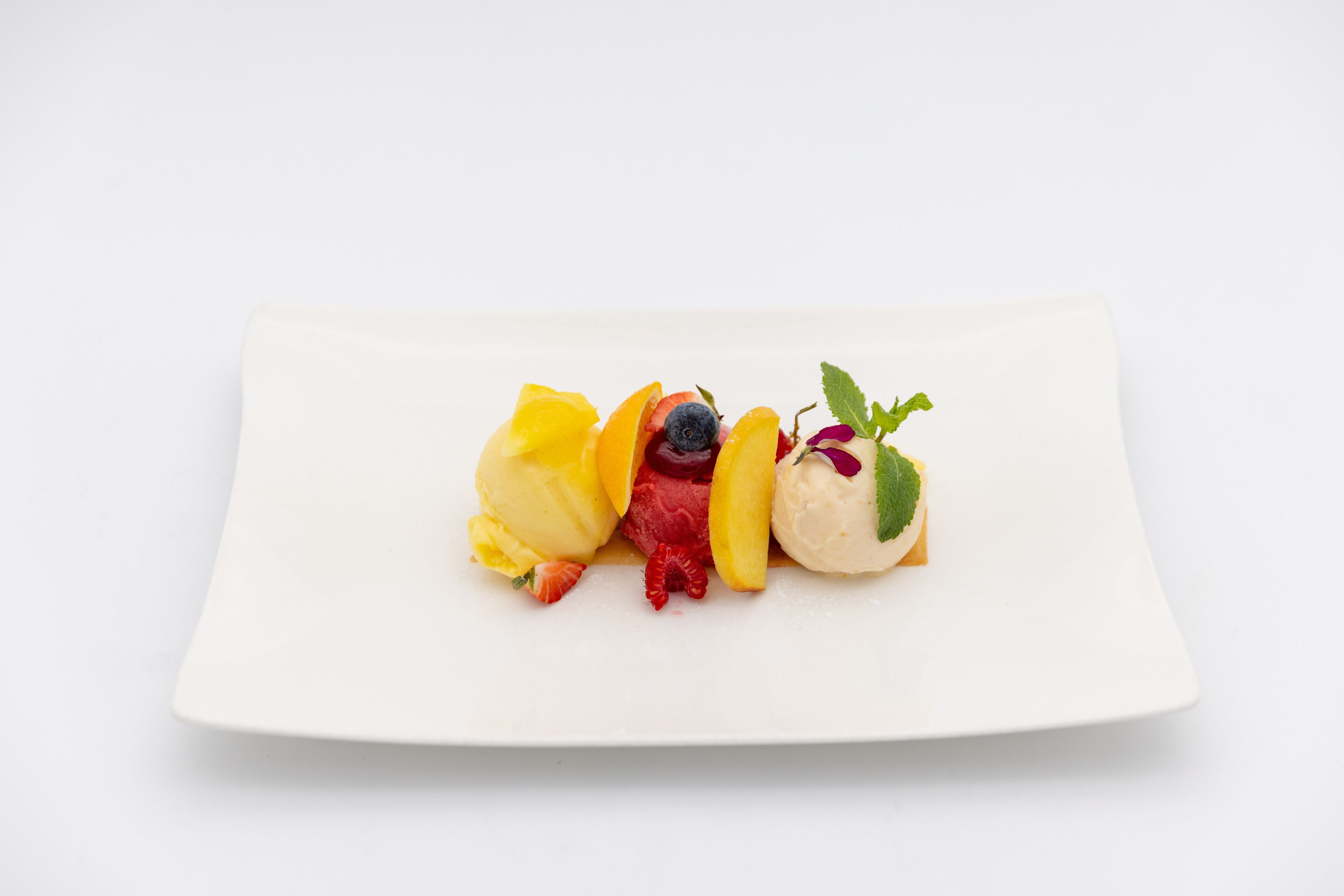 Um prato branco com três sobremesas à base de fruta.