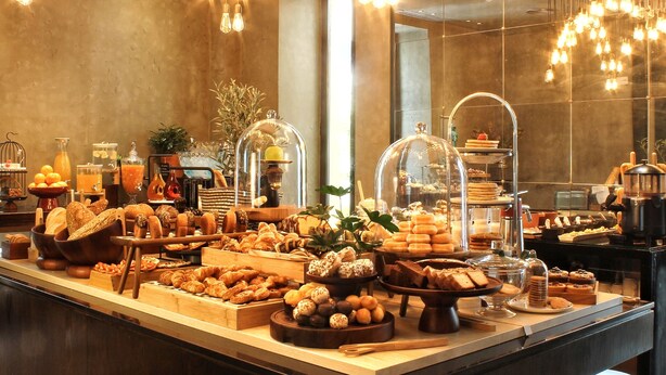 Buffet com diversos pratos e decoração moderna com luminárias pendentes.