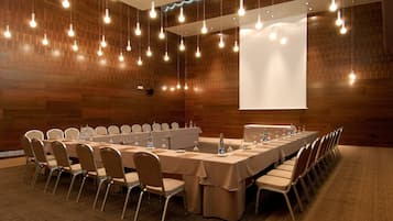 Uma sala de conferências com uma mesa comprida, cadeiras e um projetor.