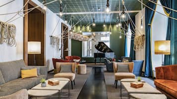 Um hall amplo com um piano de cauda, diversas áreas de estar e um design moderno de lustre.