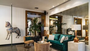 Uma sala de estar moderna com um sofá verde, uma escultura de cavalo e um espelho grande.