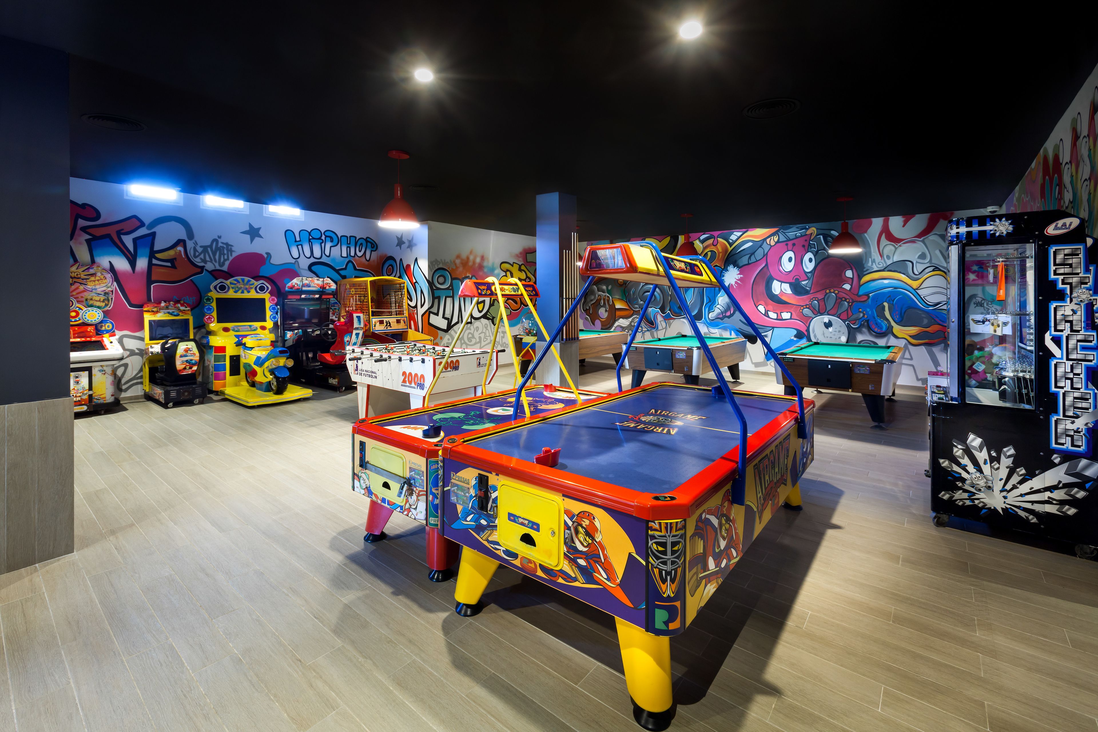 Um salão de jogos indoor com máquinas de jogos coloridas e uma mesa de bilhar.