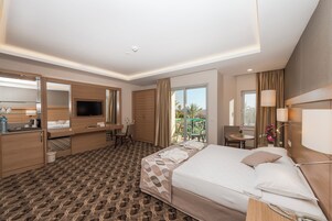 Quarto de hotel moderno com cama grande, televisão, escrivaninha e varanda com vista.