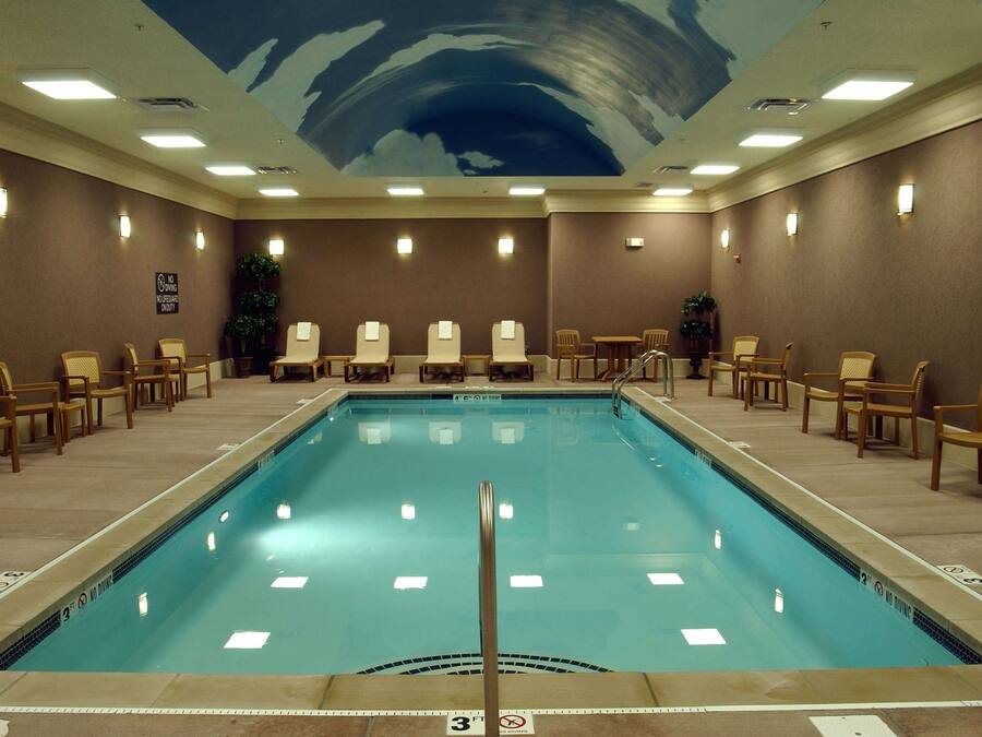 Um saguão de hotel com piscina, cadeiras e um mural no teto.