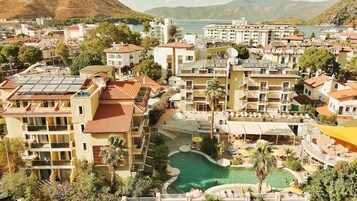 Um resort com vários edifícios, uma piscina central e vista para o mar.