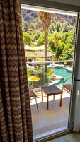 Uma varanda com vista para uma piscina, cadeiras e uma mesa.