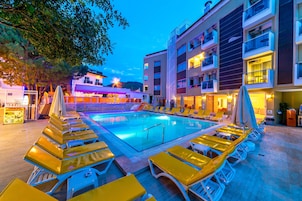Uma área de piscina com espreguiçadeiras e um edifício com varandas.
