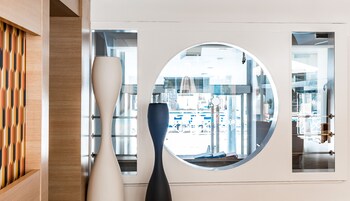 Um interior moderno com uma grande janela circular, lambris de madeira e dois vasos.