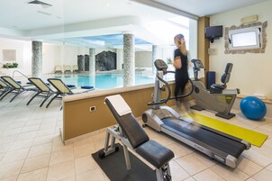 Uma academia com piscina, equipamentos de ginástica e esteira.