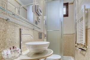 Um banheiro moderno com uma pia grande e branca, box de chuveiro em vidro e porta de vidro.
