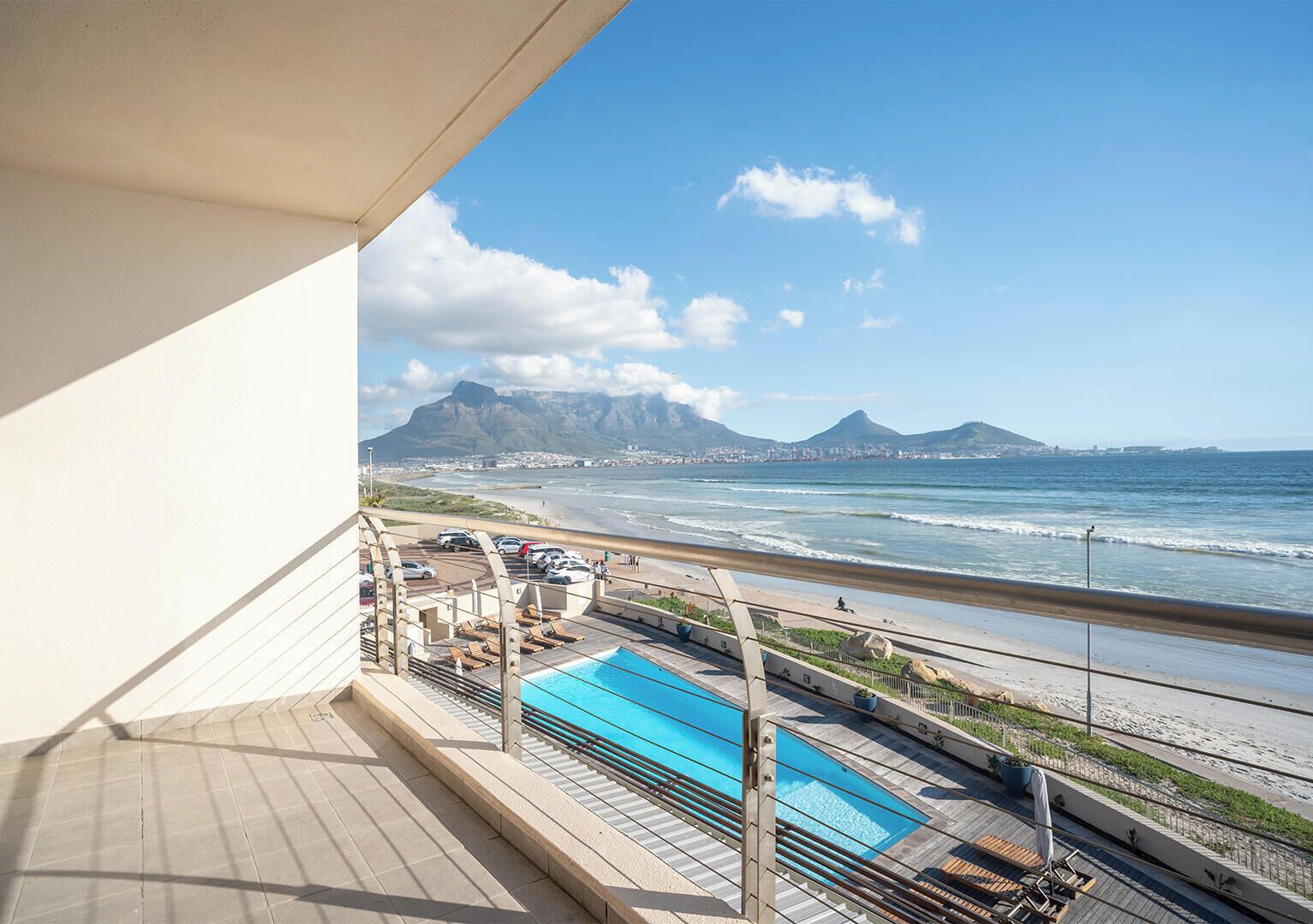Uma varanda com vista para o mar, uma piscina e uma área de estacionamento.