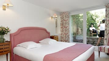 Quarto com cama grande, mesa de cabeceira, luminária, cômoda e janela com cortinas.