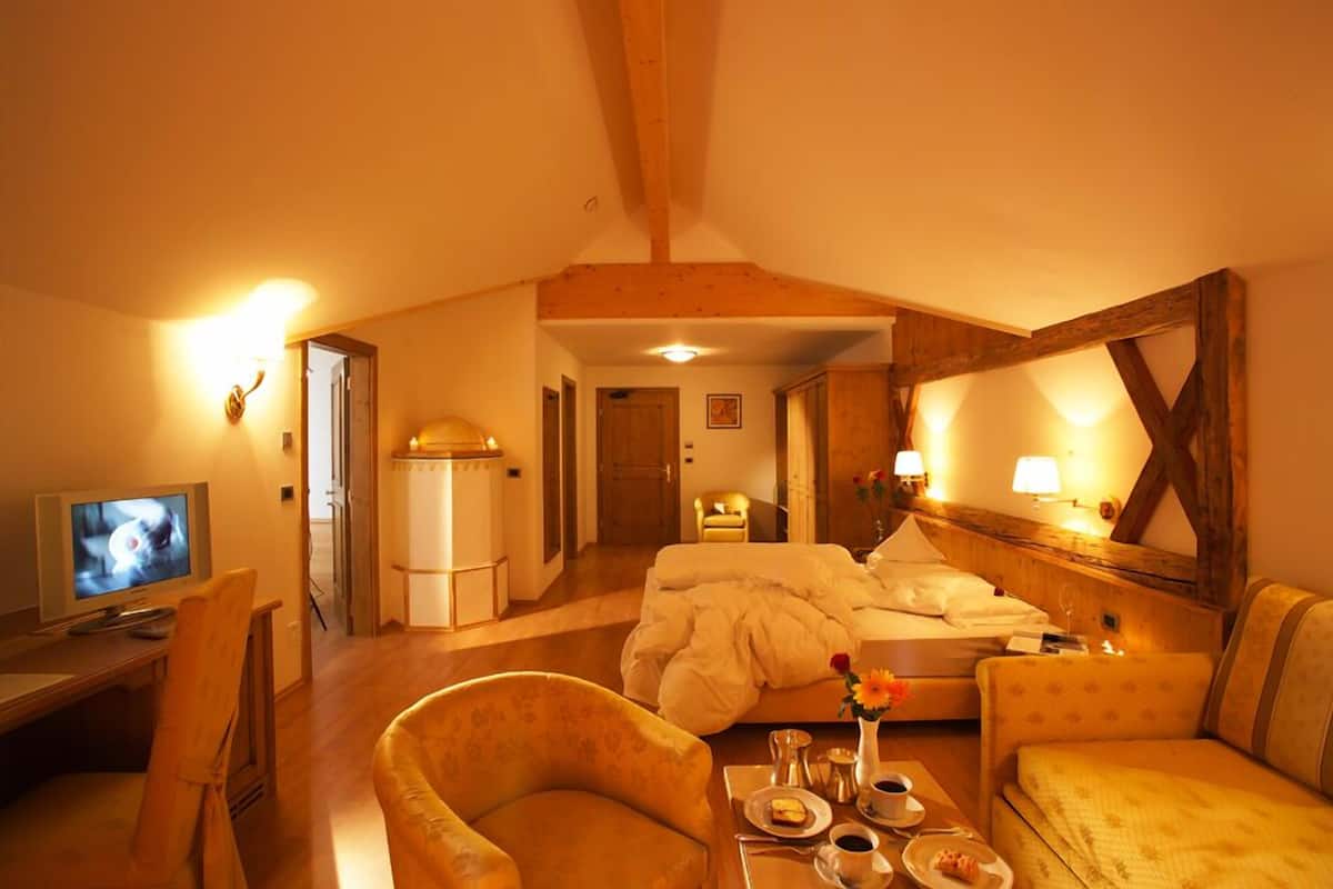 Quarto de hotel acolhedor com cama, escrivaninha, cadeira e televisão.