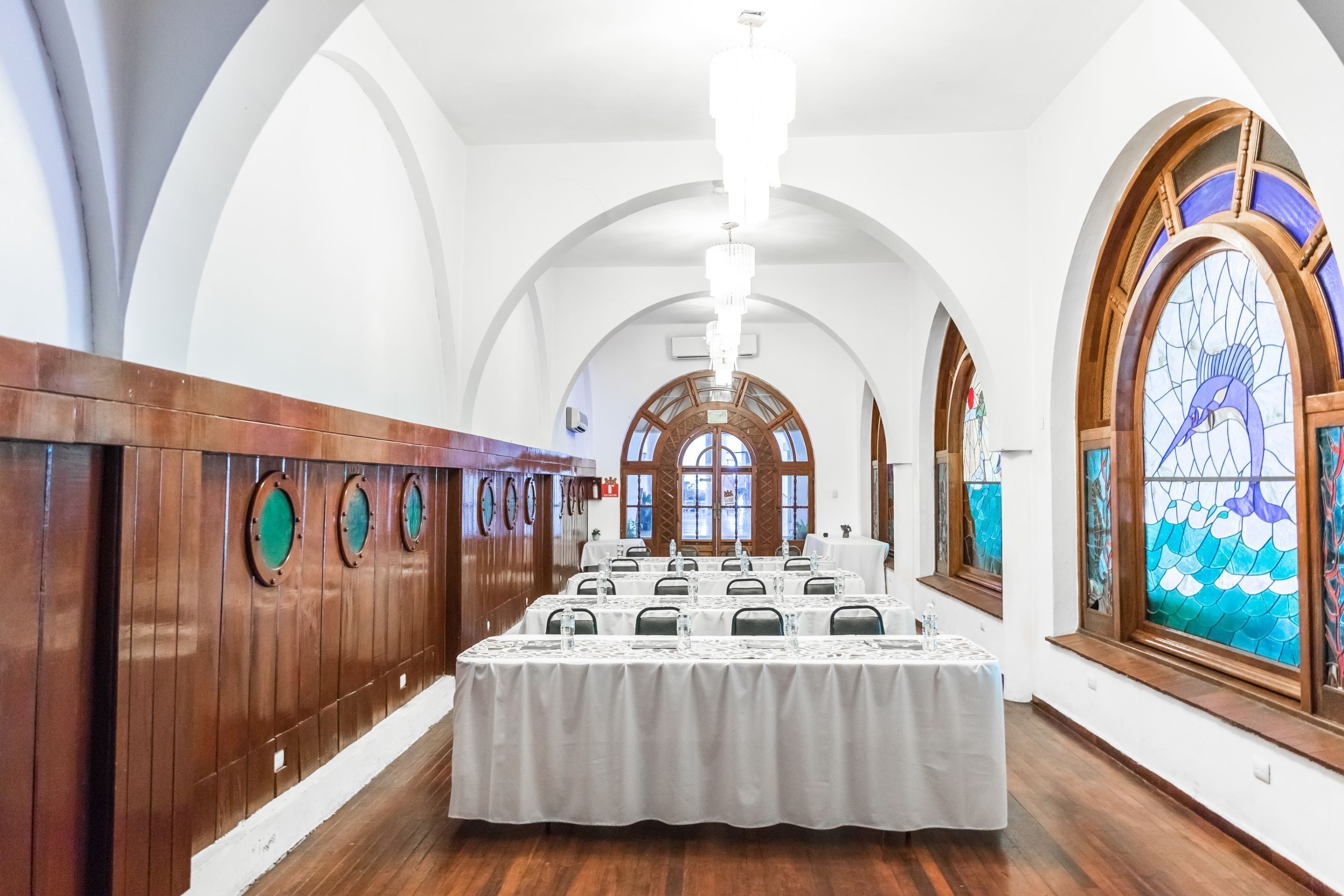 Uma sala de banquetes com painéis de madeira, tetos abobadados e janelas de vitrais.