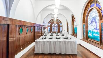 Uma sala de banquetes com painéis de madeira, tetos abobadados e janelas de vitrais.