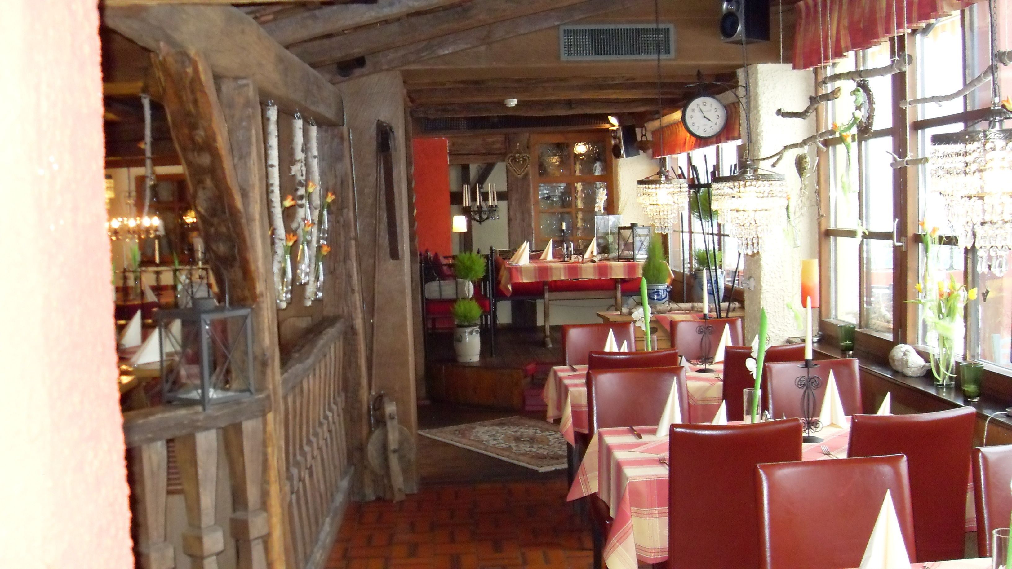 Interior acolhedor de restaurante, com vigas de madeira, toalhas de mesa xadrez vermelho e branco e um ambiente rústico.