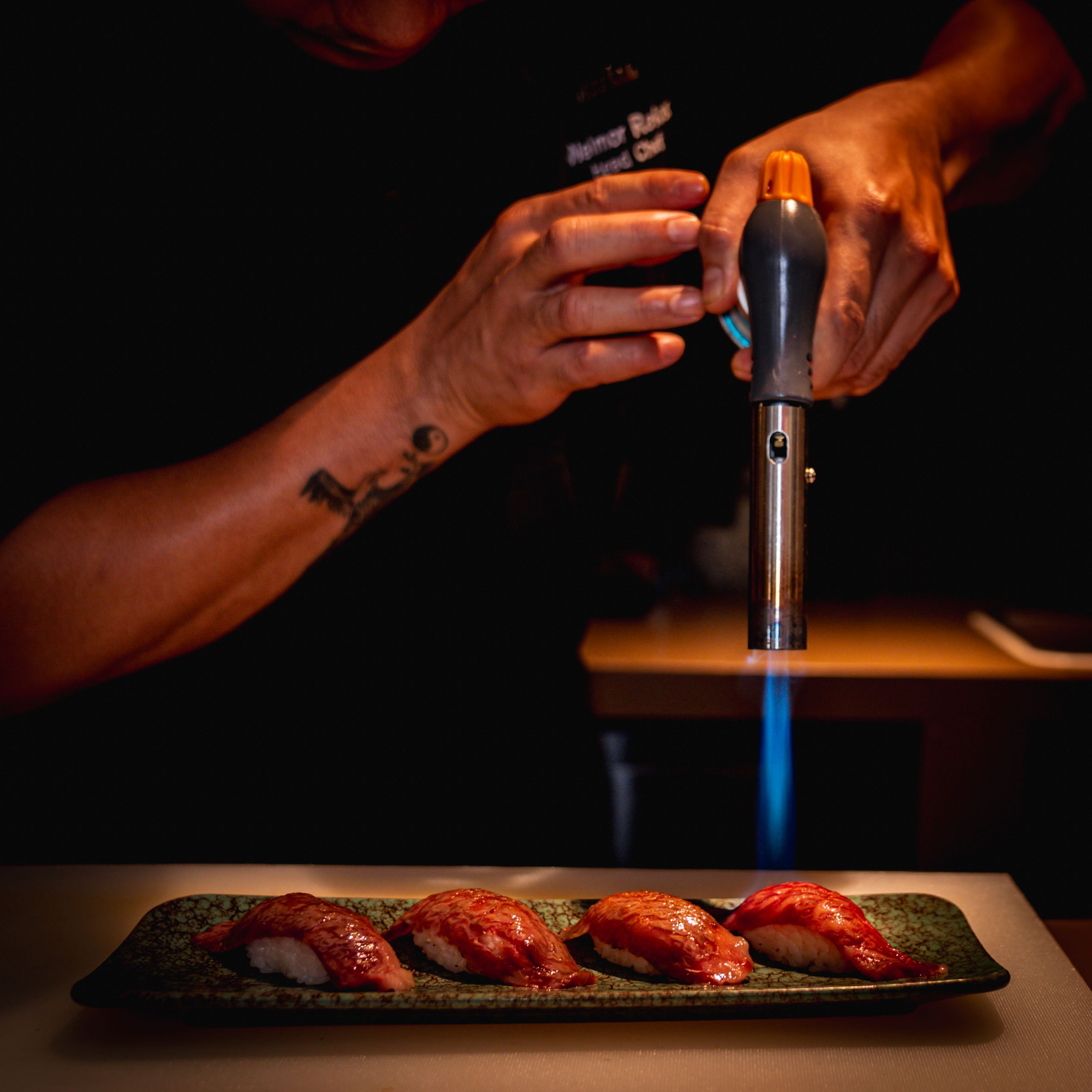 Uma pessoa preparando sushi com um maçarico.
