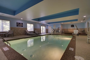 Piscina interna com espreguiçadeiras, cadeira de salva-vidas e placa de proibição de mergulho.