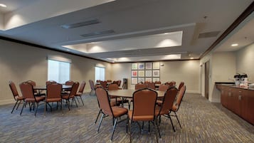Sala de conferência com uma mesa grande e várias cadeiras, piso coberto de carpete e dutos de ventilação no teto.