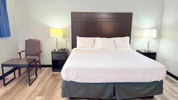 Quarto de hotel com uma cama grande, duas mesas de cabeceira com luminárias, uma escrivaninha e uma cadeira.