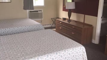 Quarto com duas camas, cômoda, televisão e janela com cortinas.
