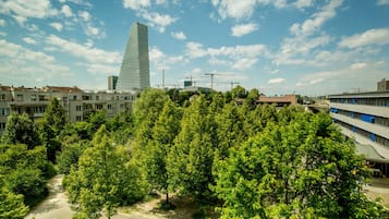 Um edifício moderno com design singular, cercado por árvores verdes exuberantes e céu azul límpido.
